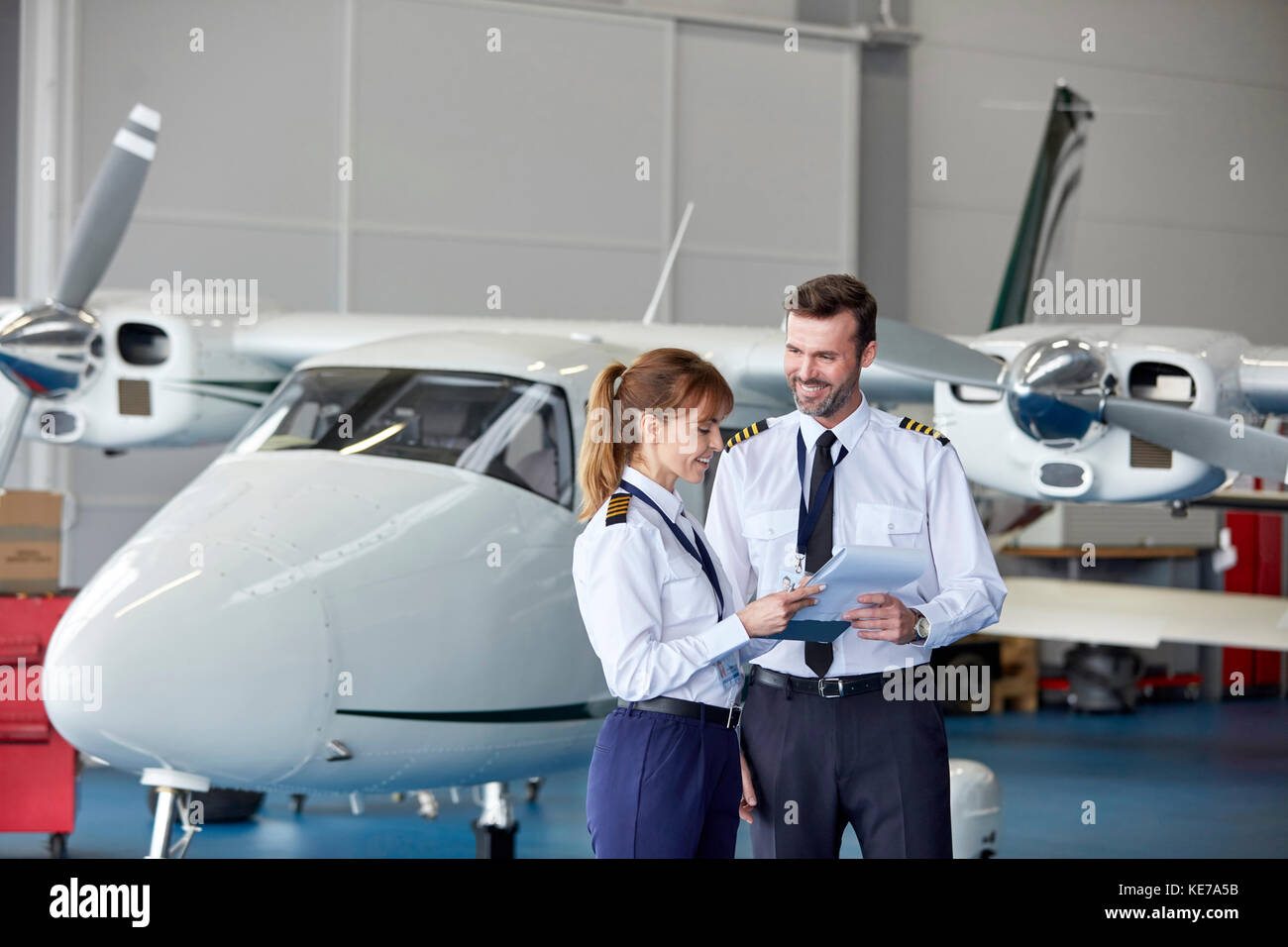 Pilots discussing paperwork near airplane in hangar Stock Photo - Alamy