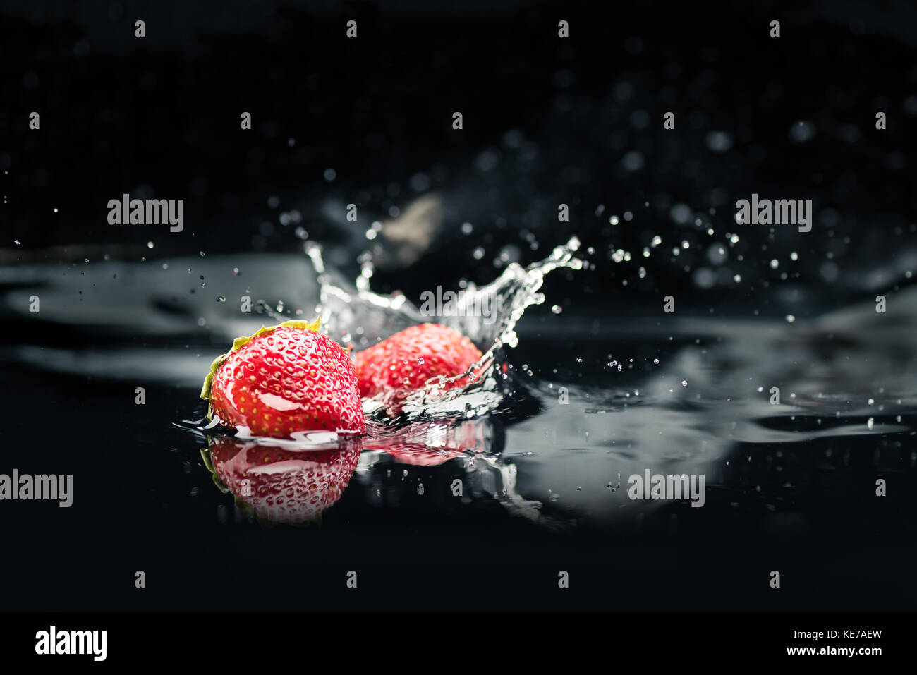 ripe strawberries falling in water Stock Photo - Alamy