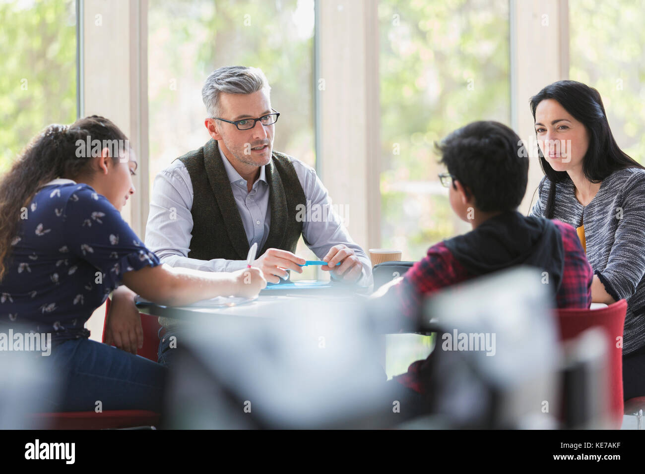 Teachers tutoring students at library table Stock Photo - Alamy
