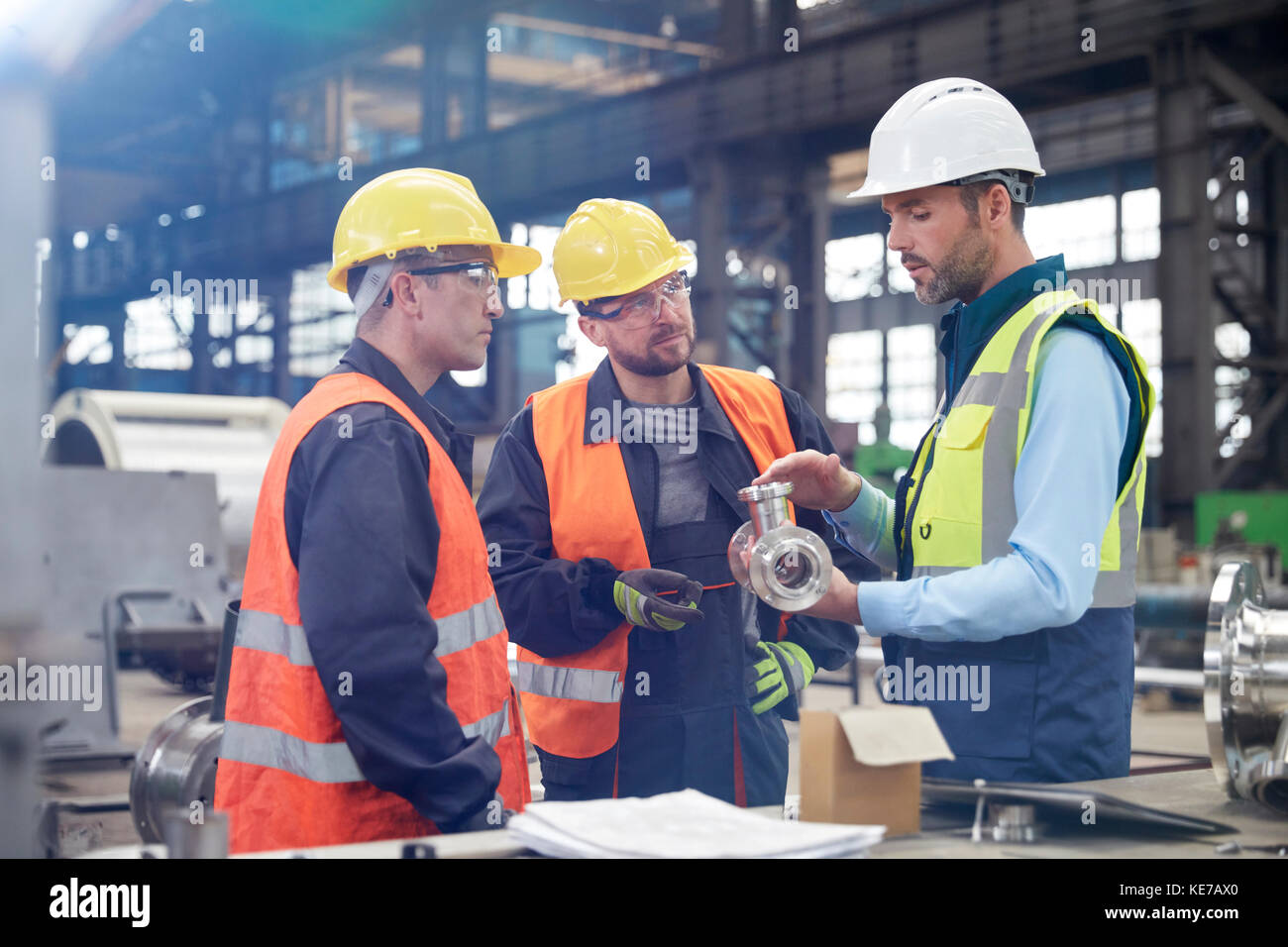 Male engineers discussing steel part in factory Stock Photo - Alamy