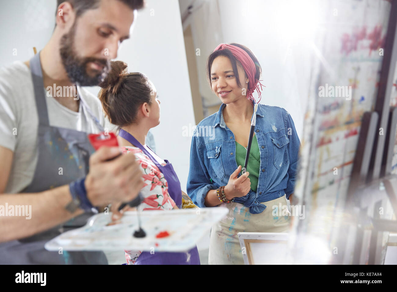 Artists talking and painting in art class studio Stock Photo - Alamy