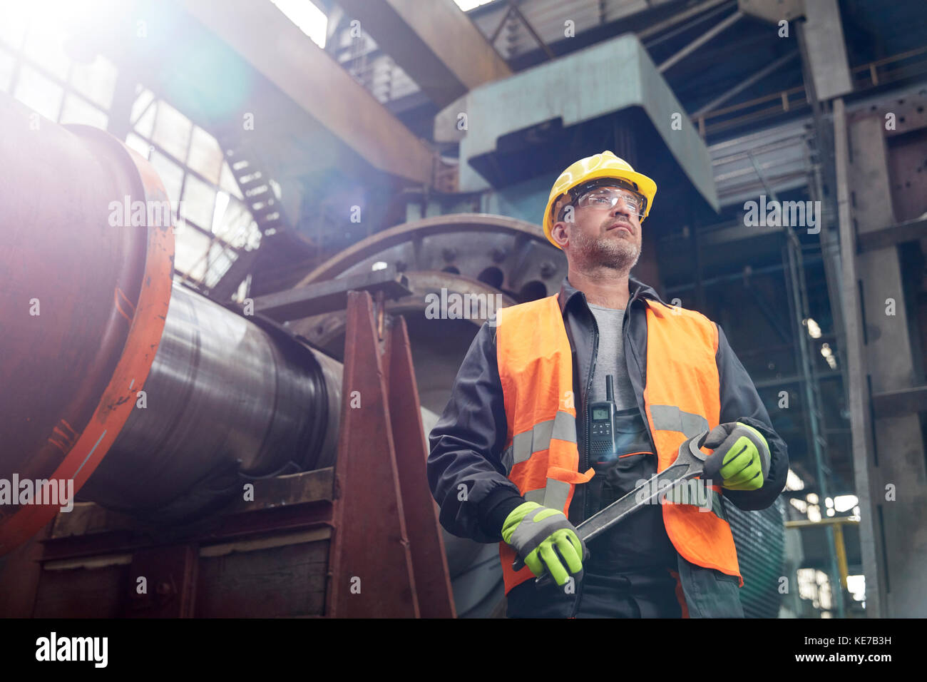 Confident male worker holding wrench in factory Stock Photo - Alamy
