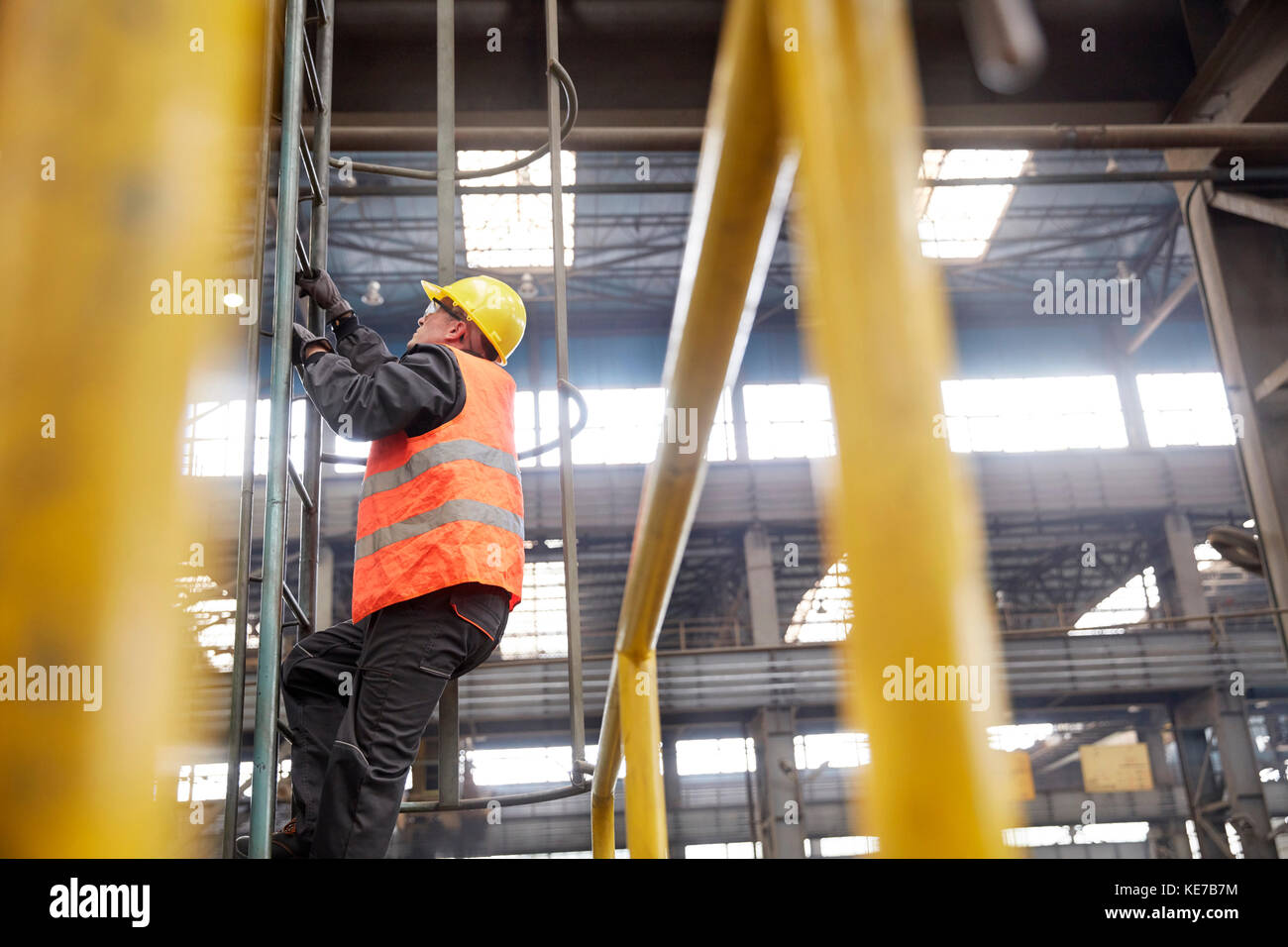 Male worker climbing ladder in factory Stock Photo - Alamy
