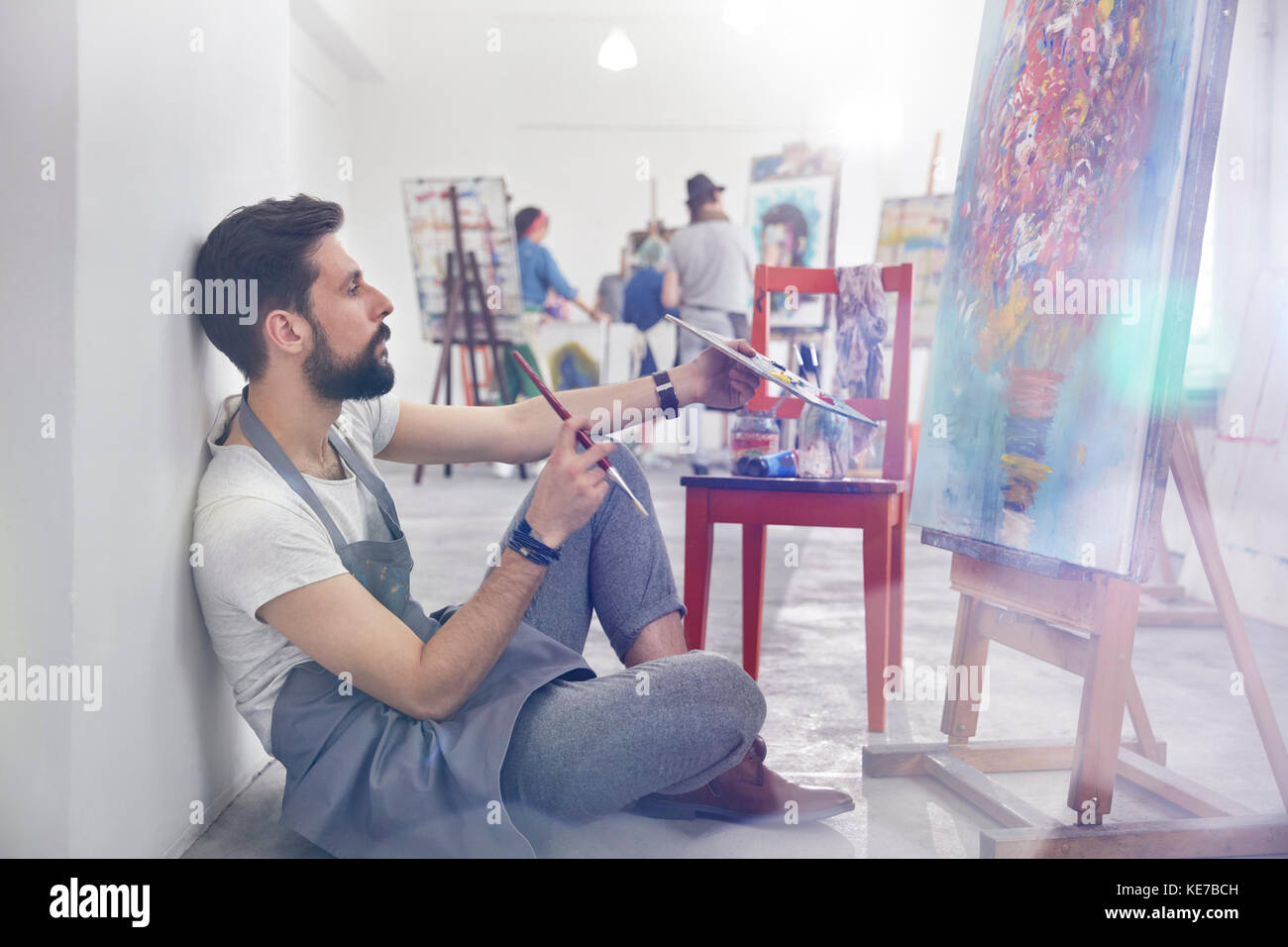 Male painter painting, examining painting in art class studio Stock ...