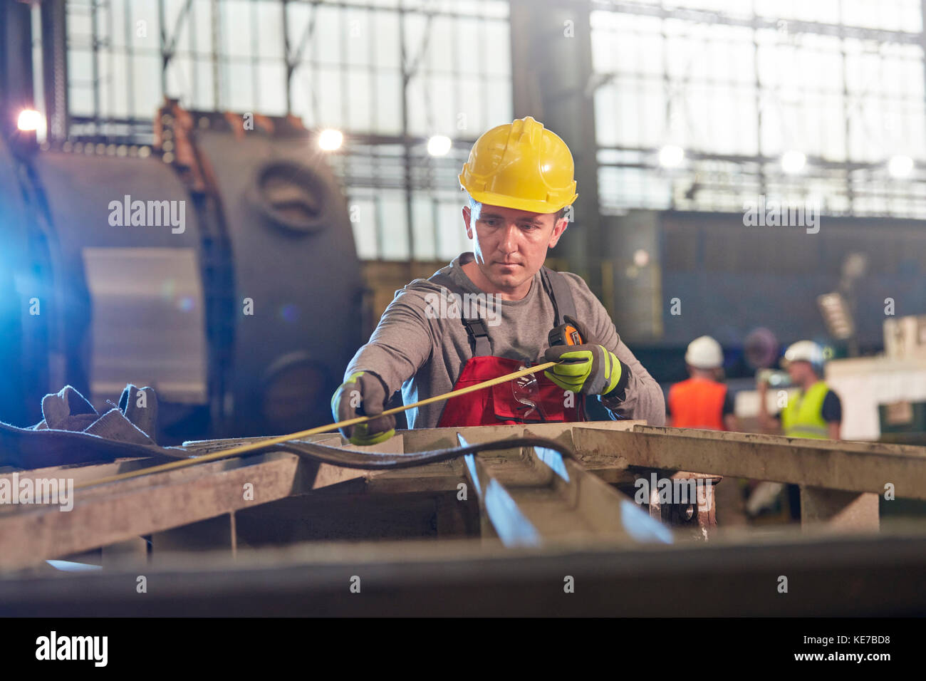 Male worker with tape measure measuring steel in factory Stock Photo ...