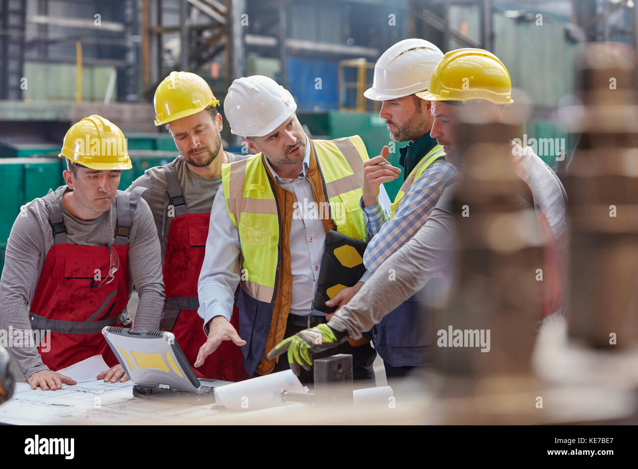 Male foreman, engineers and workers at laptop meeting, discussing ...