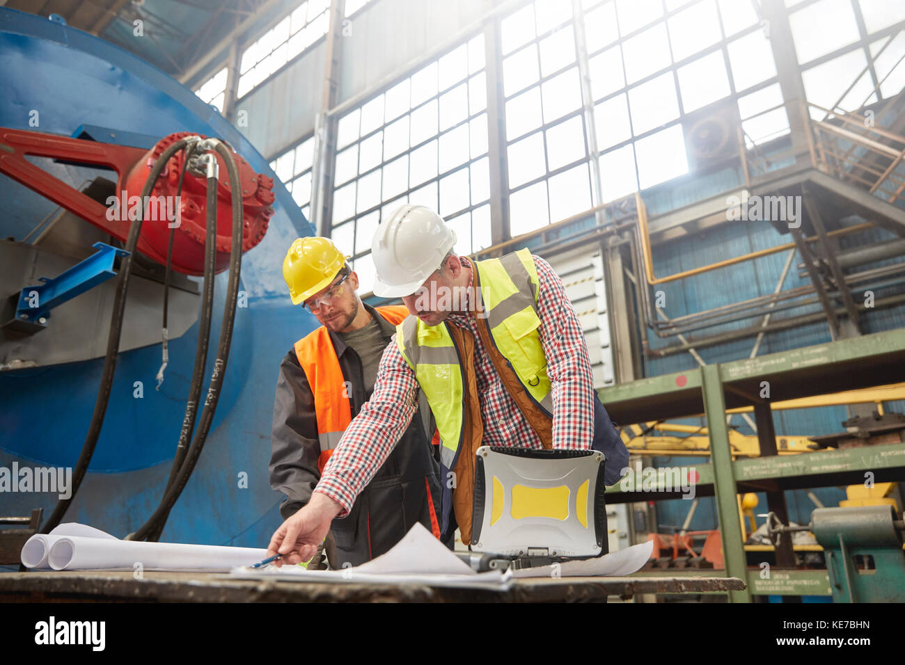 Male foreman and engineer reviewing blueprints in factory Stock Photo ...