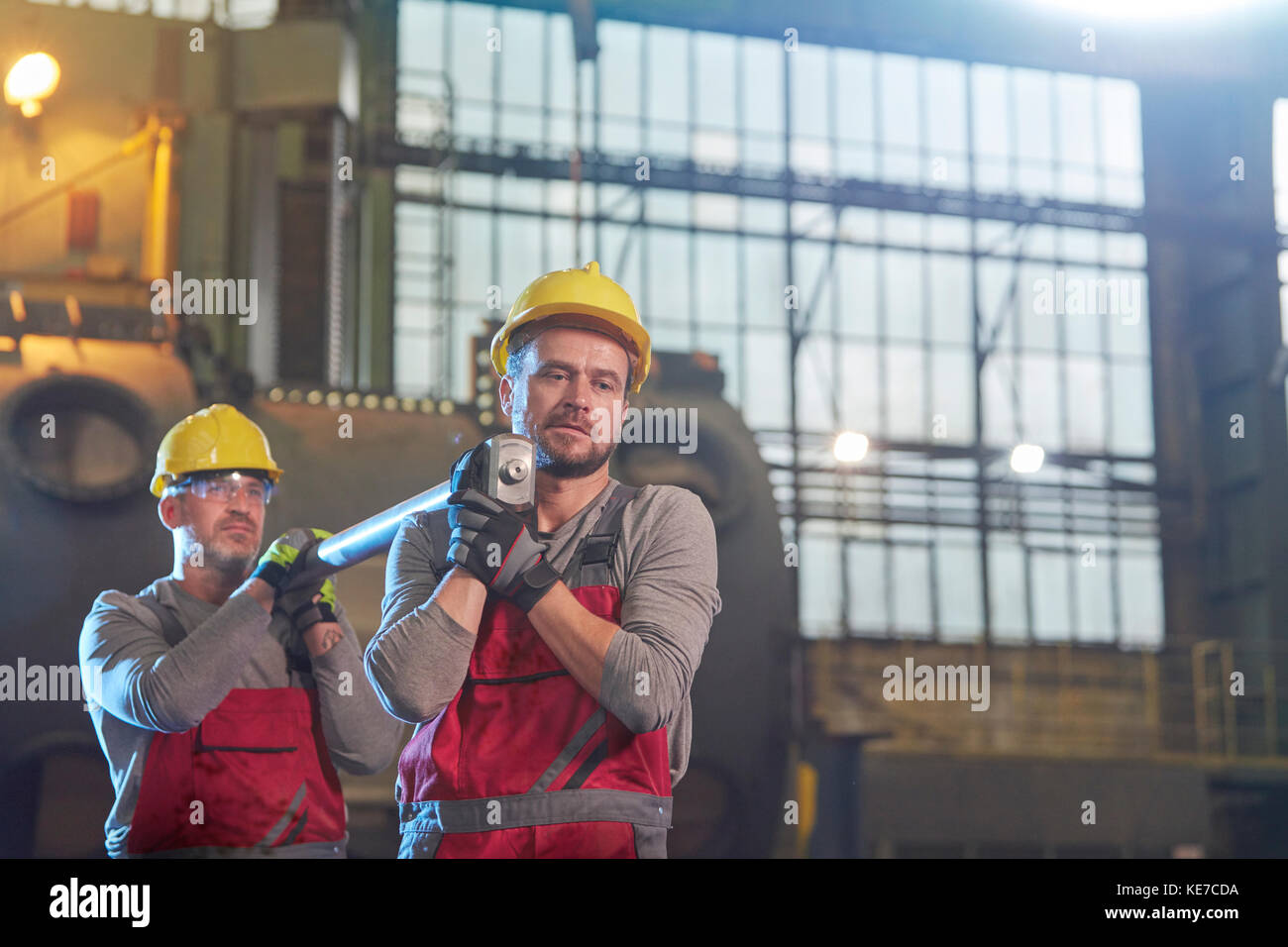 Male workers carrying steel part in factory Stock Photo - Alamy