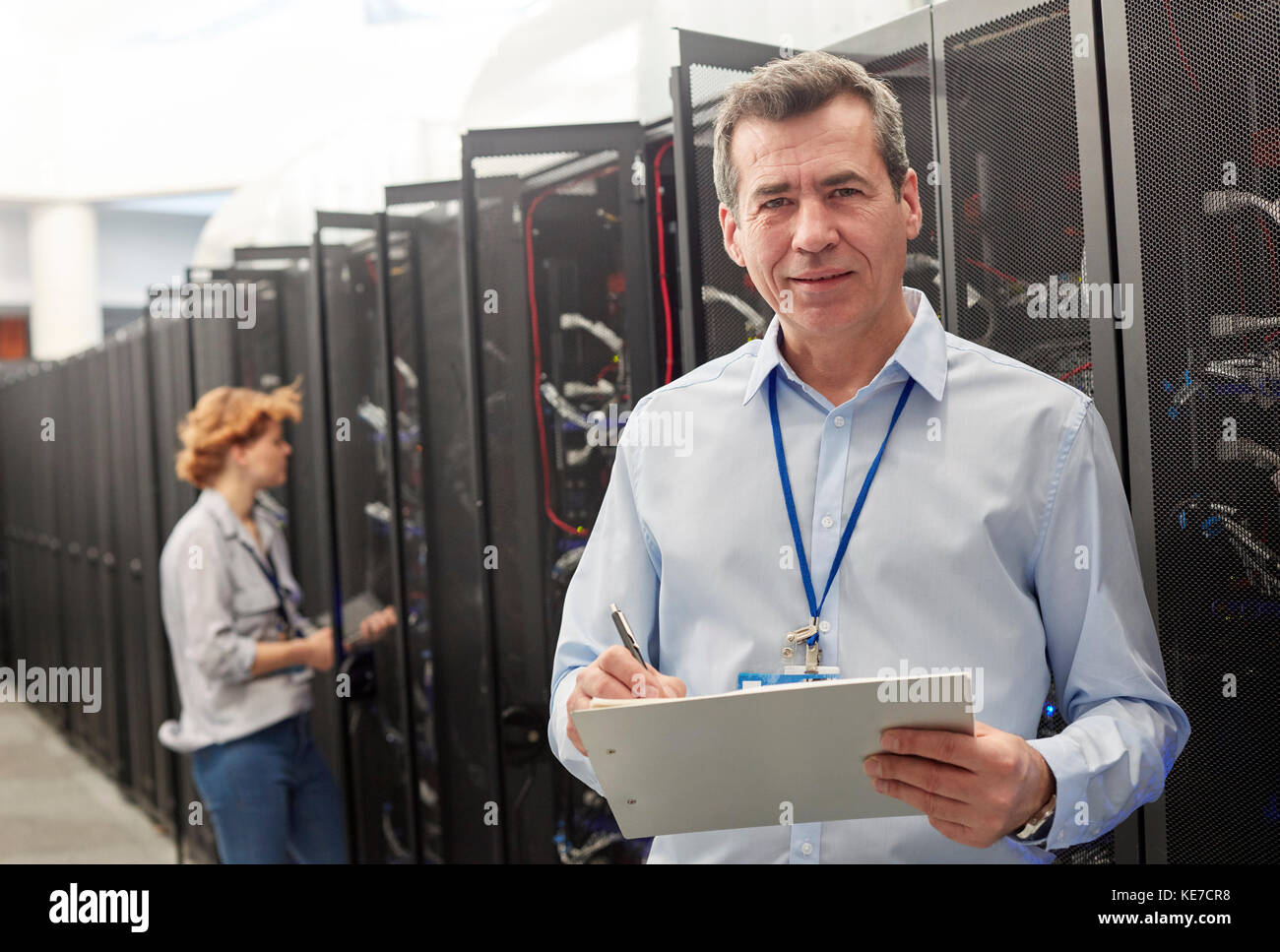 Portrait confident male IT technician with clipboard in server room ...