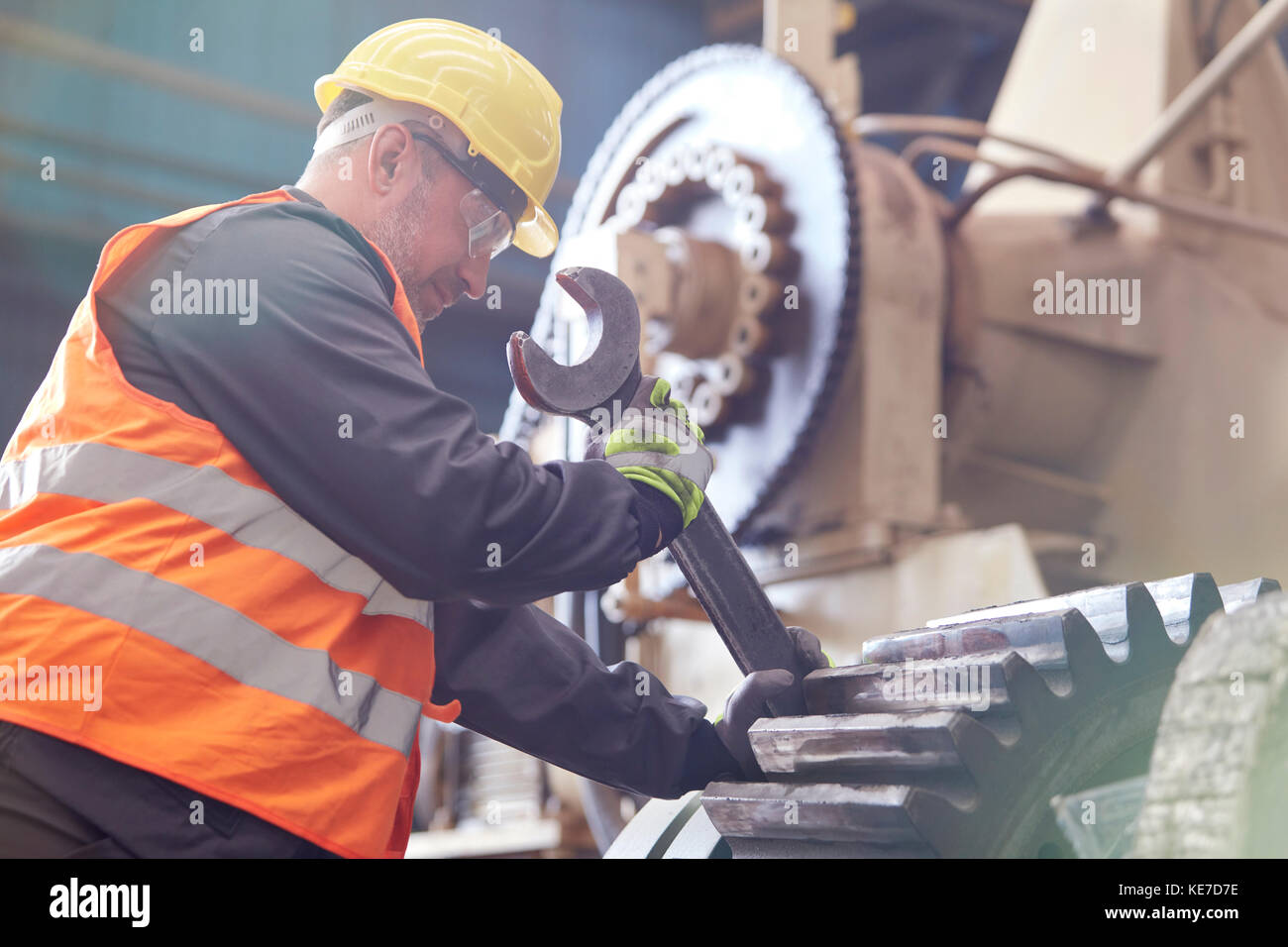 Male worker using large wrench on cog in factory Stock Photo - Alamy