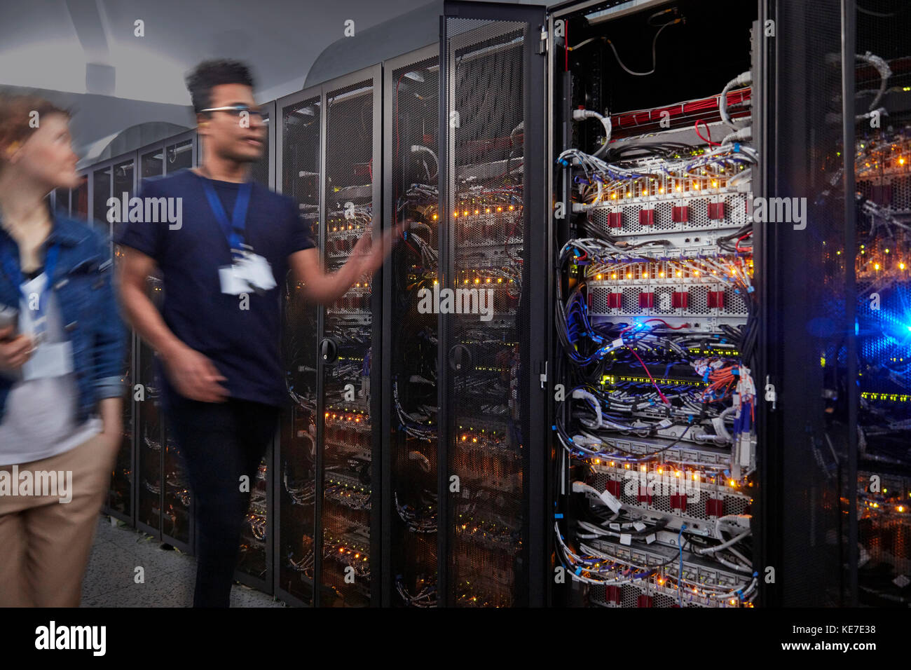 IT technicians walking along panels in server room Stock Photo - Alamy