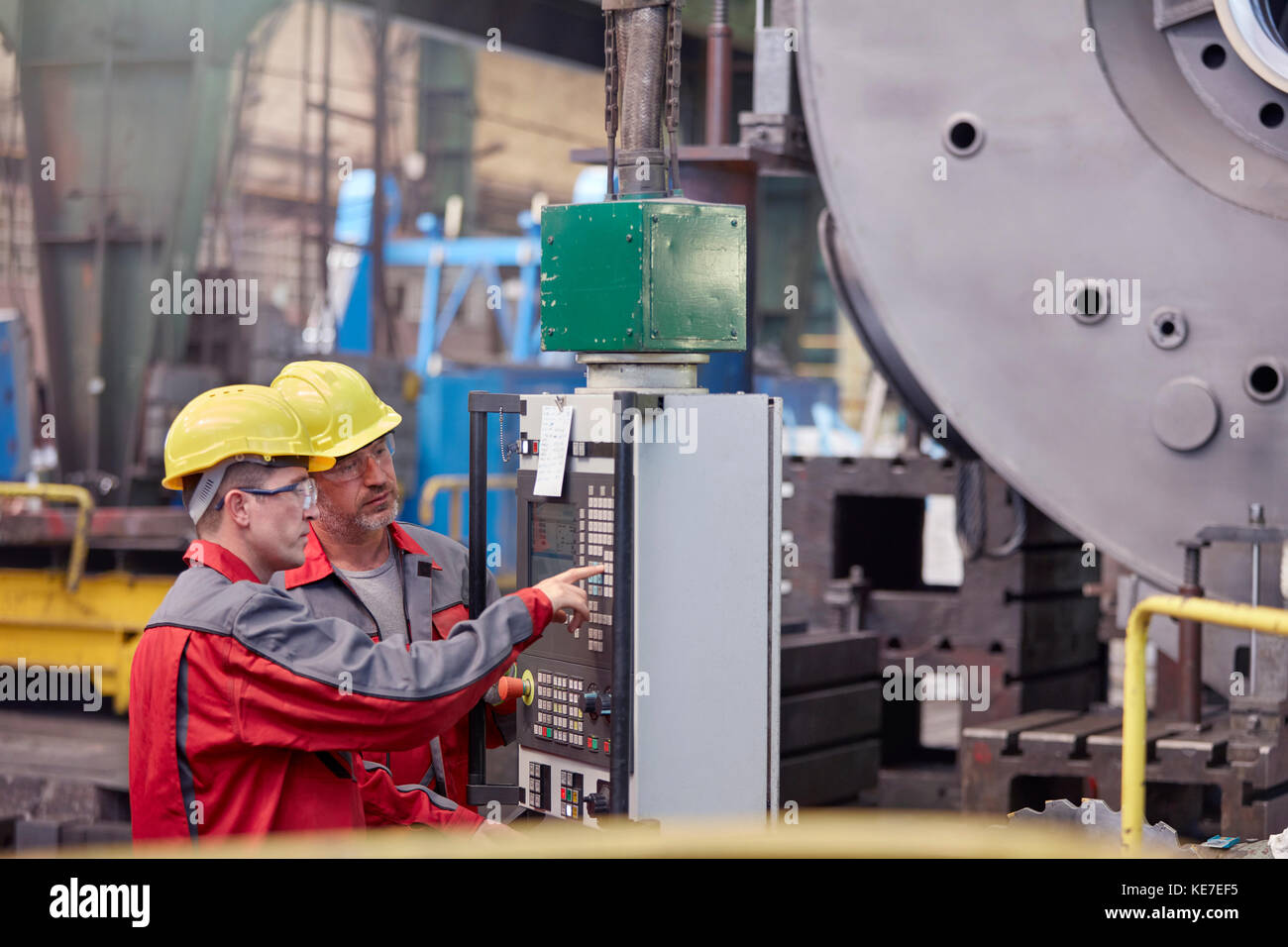 Male workers operating machinery at control panel in factory Stock ...
