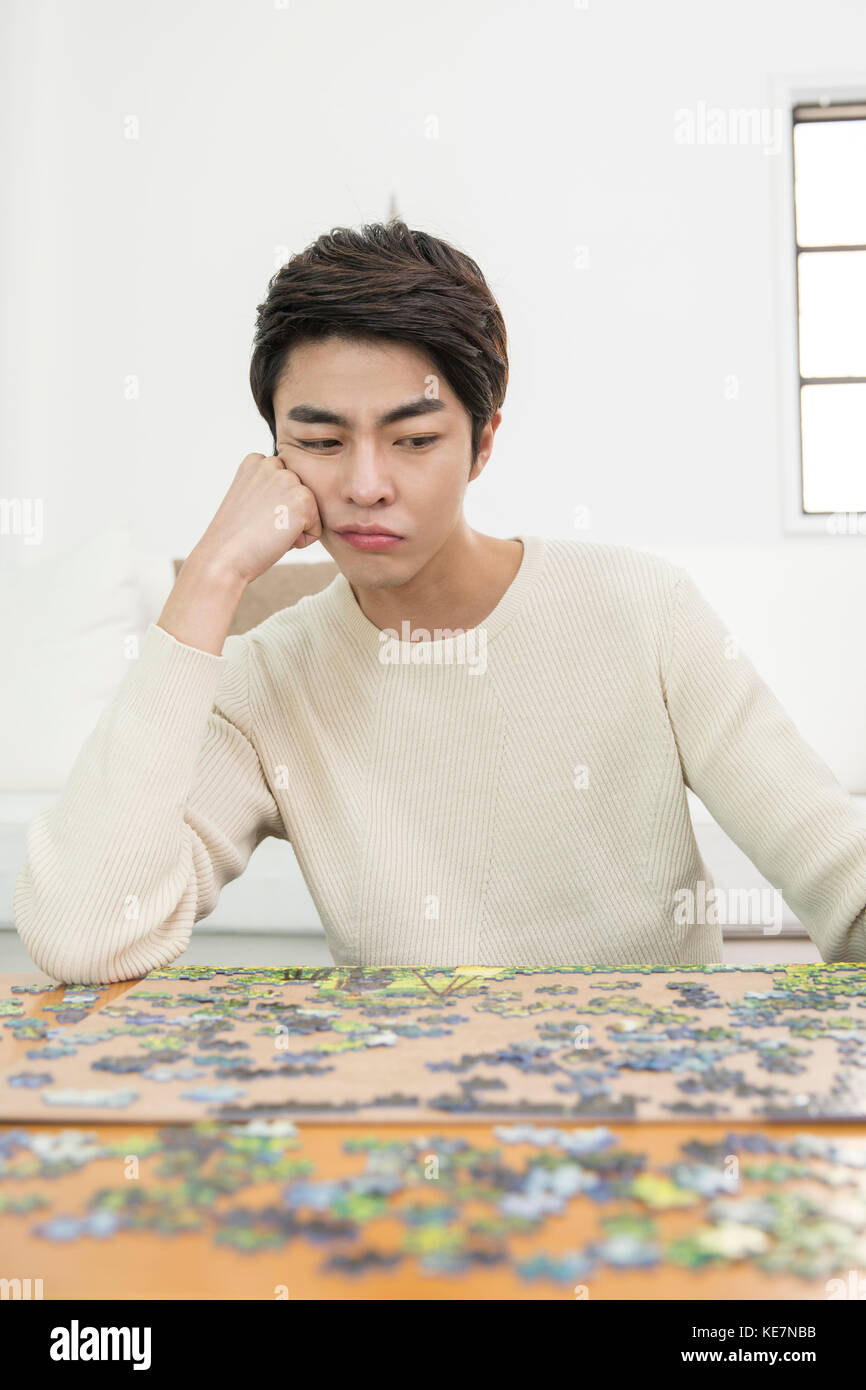 Portrait of male kidult thinking doing puzzle Stock Photo - Alamy