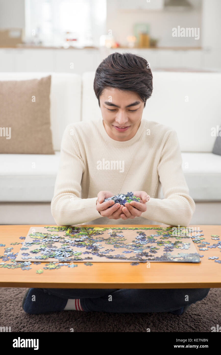 Smiling male kidult enjoying doing puzzle Stock Photo - Alamy