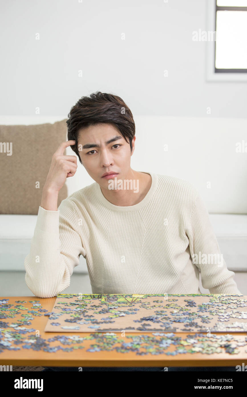 Portrait of male kidult thinking doing puzzle Stock Photo - Alamy