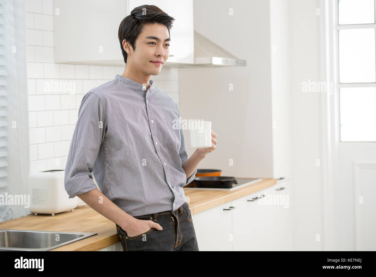 Smiling single man having teatime at kitchen Stock Photo - Alamy