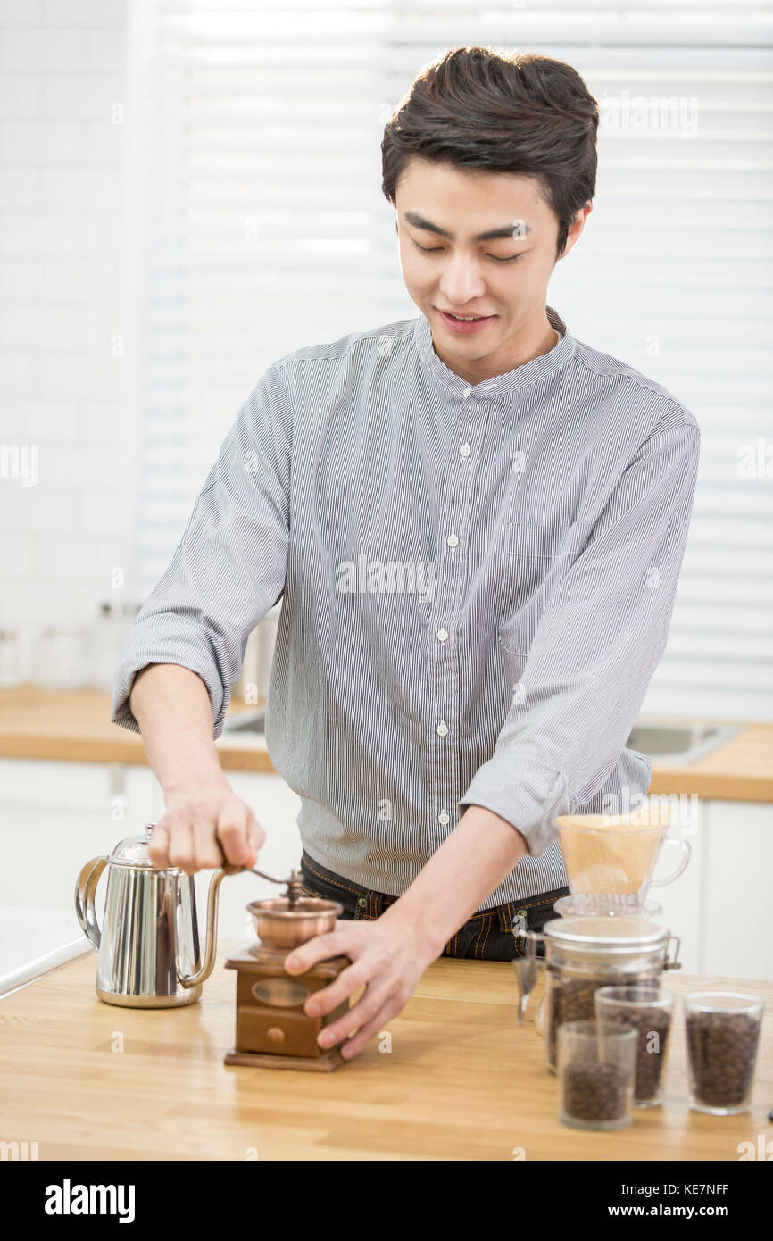 Smiling single man using a grinder at kitchen Stock Photo - Alamy