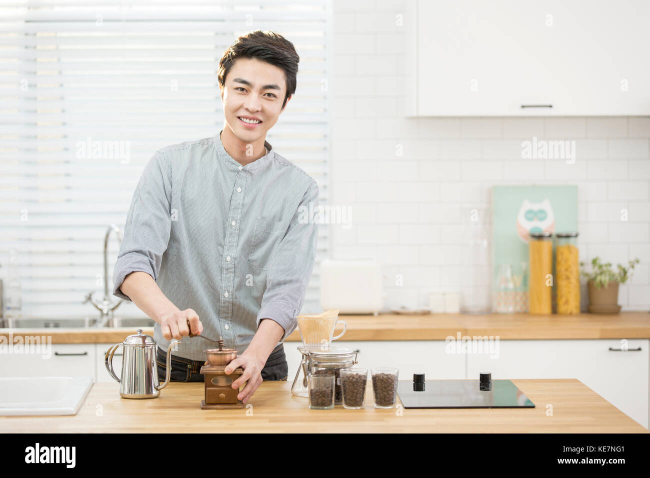 Smiling single man using a grinder at kitchen Stock Photo - Alamy