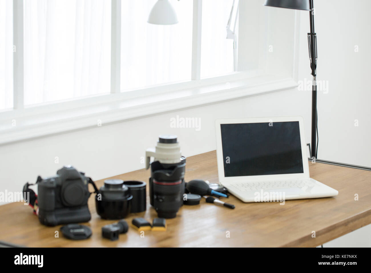 Cameras, lenses and notebook computer on a table Stock Photo - Alamy
