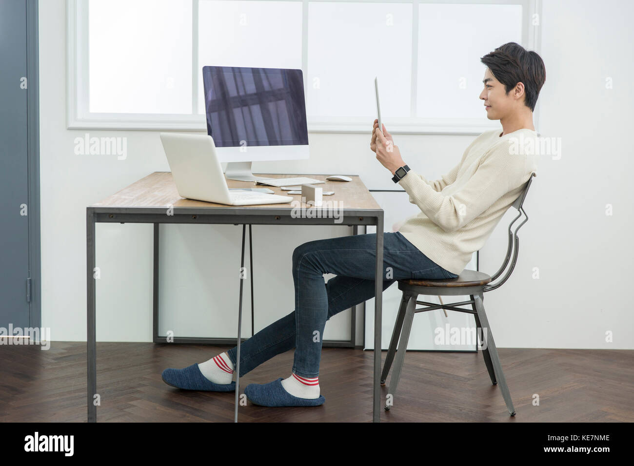 Side view of smiling man using electric tablet with various mobile ...