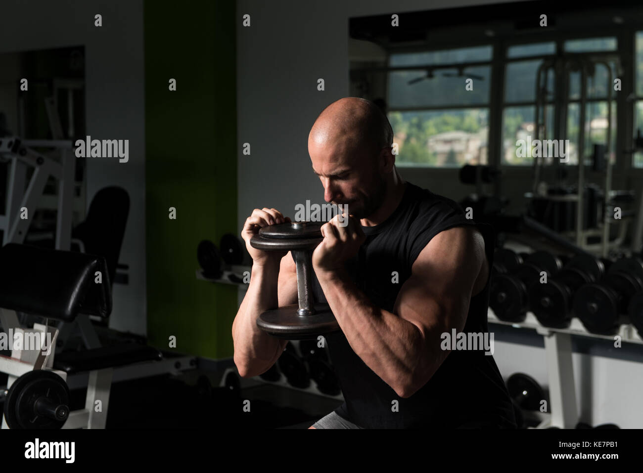 Strong Man In The Gym Exercising Quadriceps And Glutes With Dumbbells ...