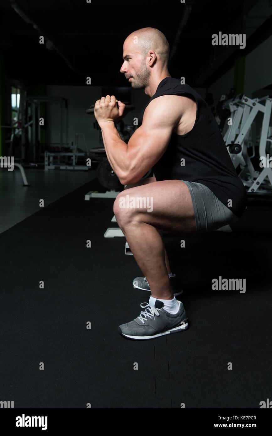 Strong Man In The Gym Exercising Hamstrings With Dumbbells - Muscular ...