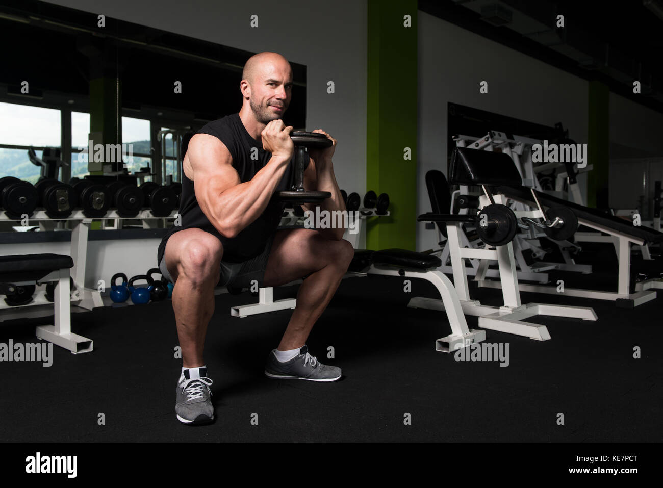 Strong Man In The Gym Exercising Legs With Dumbbells - Muscular ...