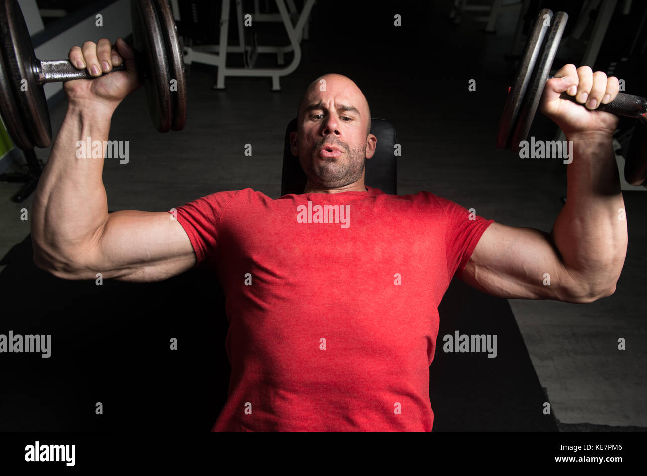Strong Man In The Gym And Exercising Chest With Dumbbells - Muscular ...