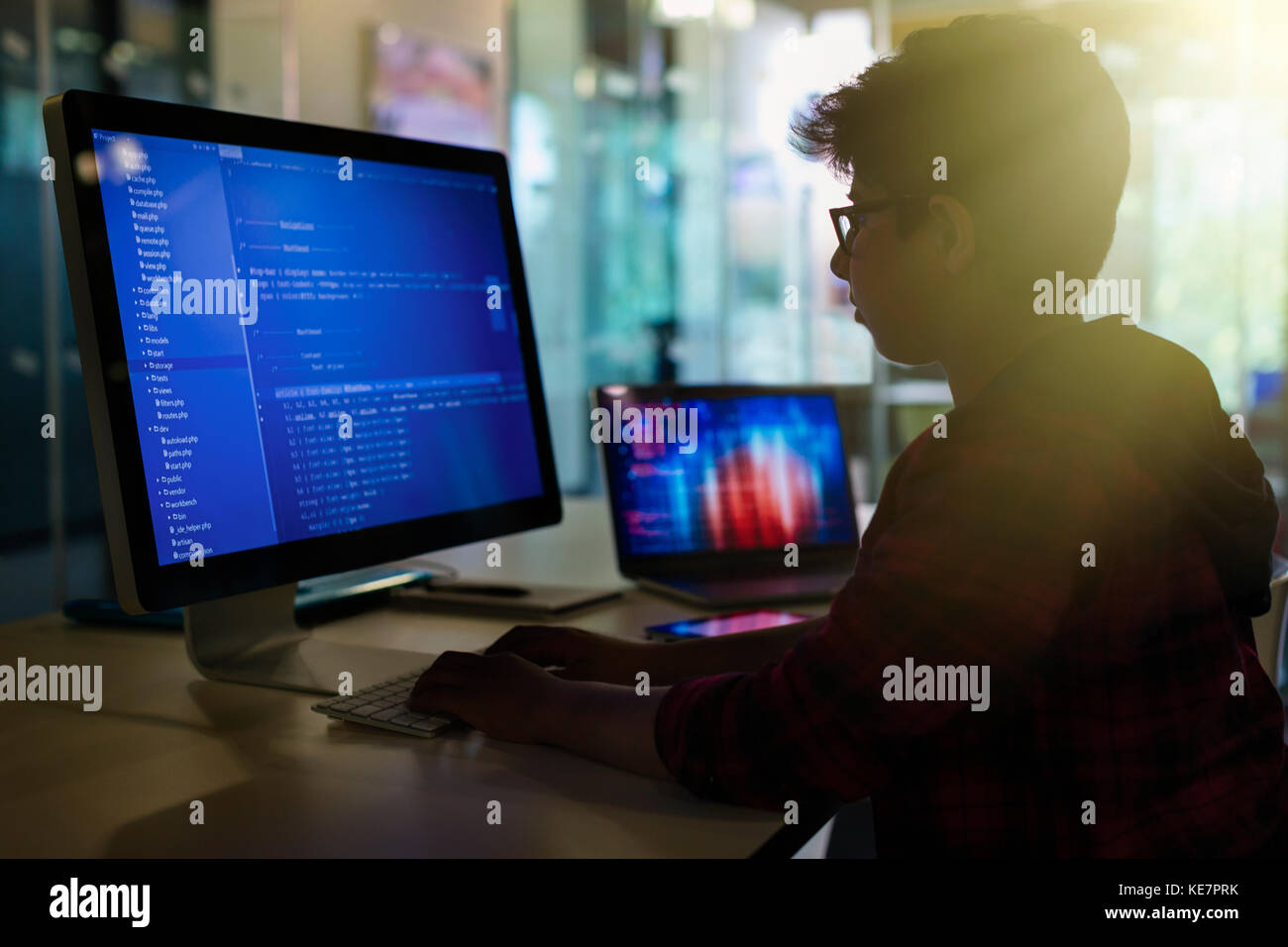 Boy student programming at computer in dark classroom Stock Photo - Alamy