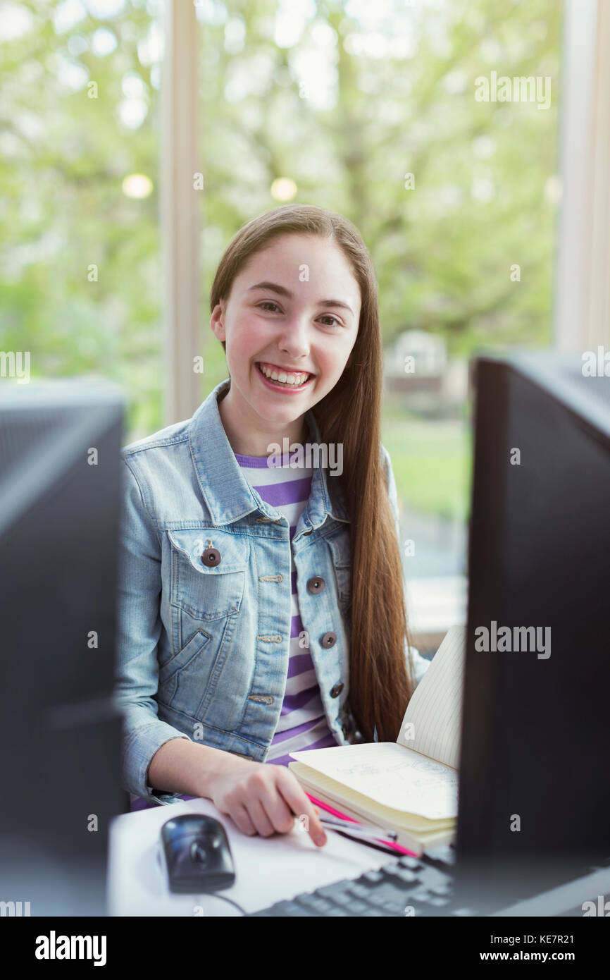 Portrait smiling, confident girl student researching at computer in ...