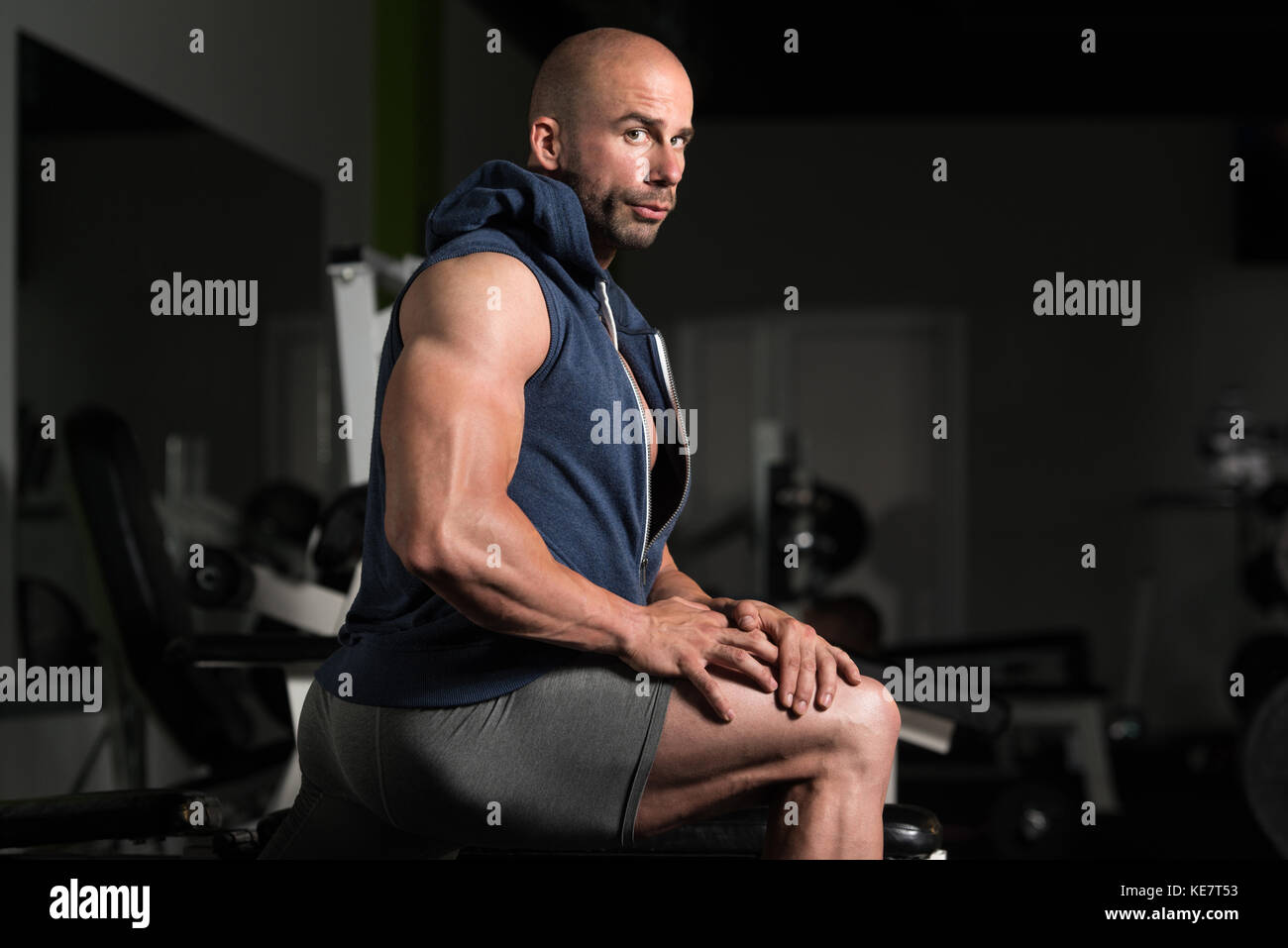 Muscular Man Stretching His Leg At The Floor In A Gym And Flexing ...