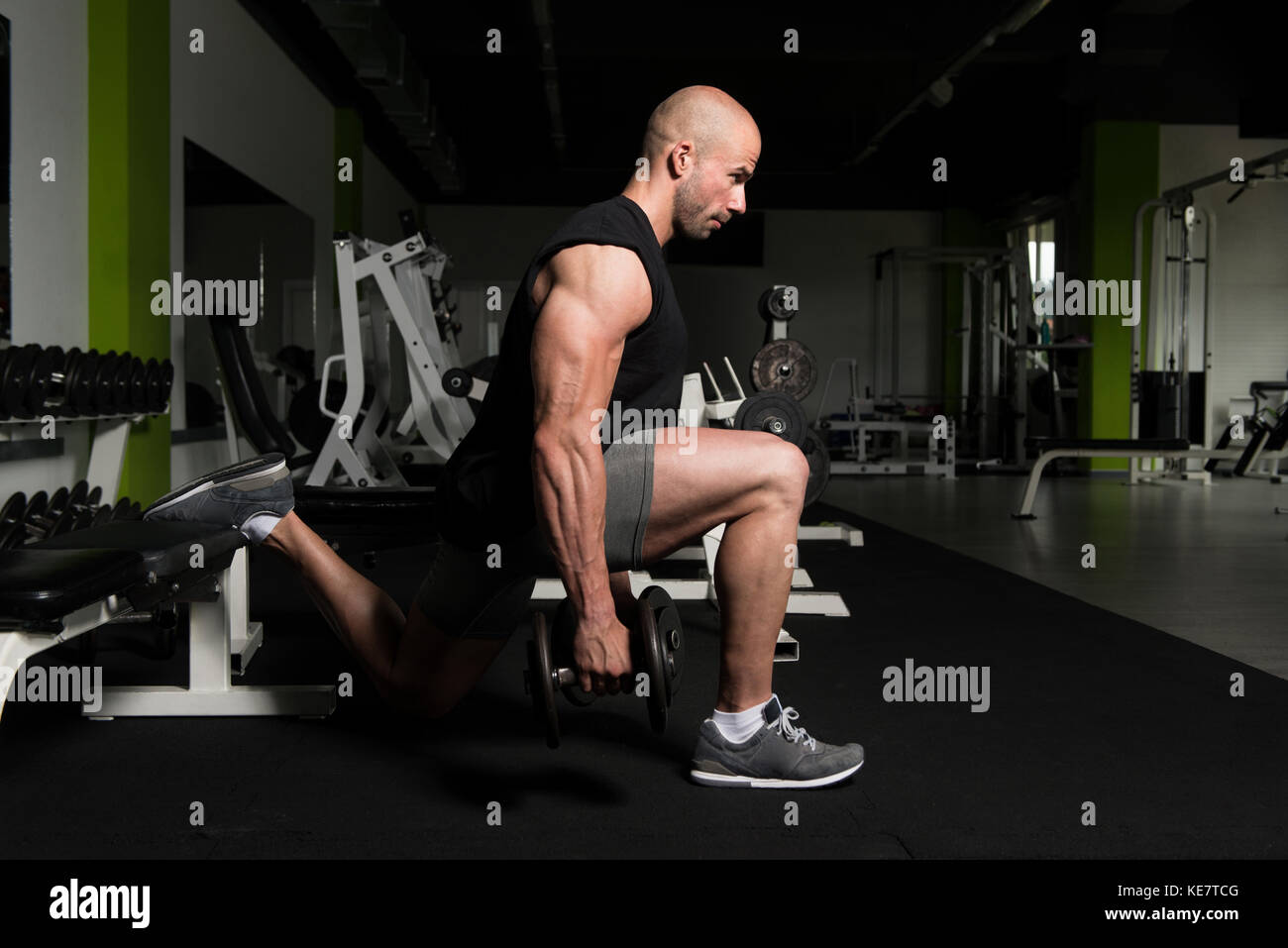 Strong Man In The Gym Exercising Hamstrings With Dumbbells - Muscular ...