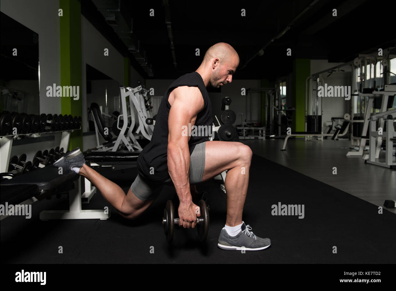 Strong Man In The Gym Exercising Quadriceps And Glutes With Dumbbells ...
