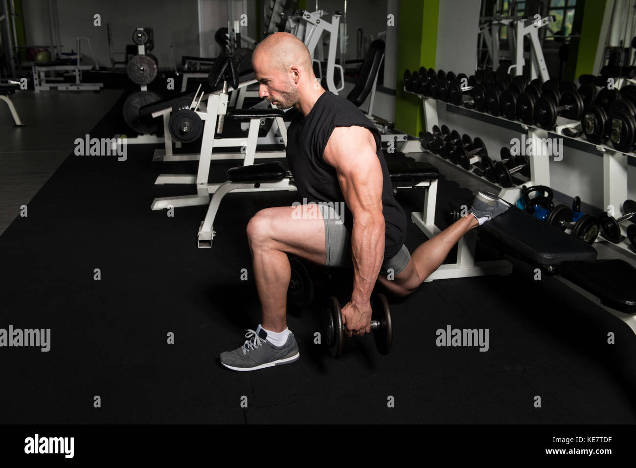 Strong Man In The Gym Exercising Hamstrings With Dumbbells - Muscular ...