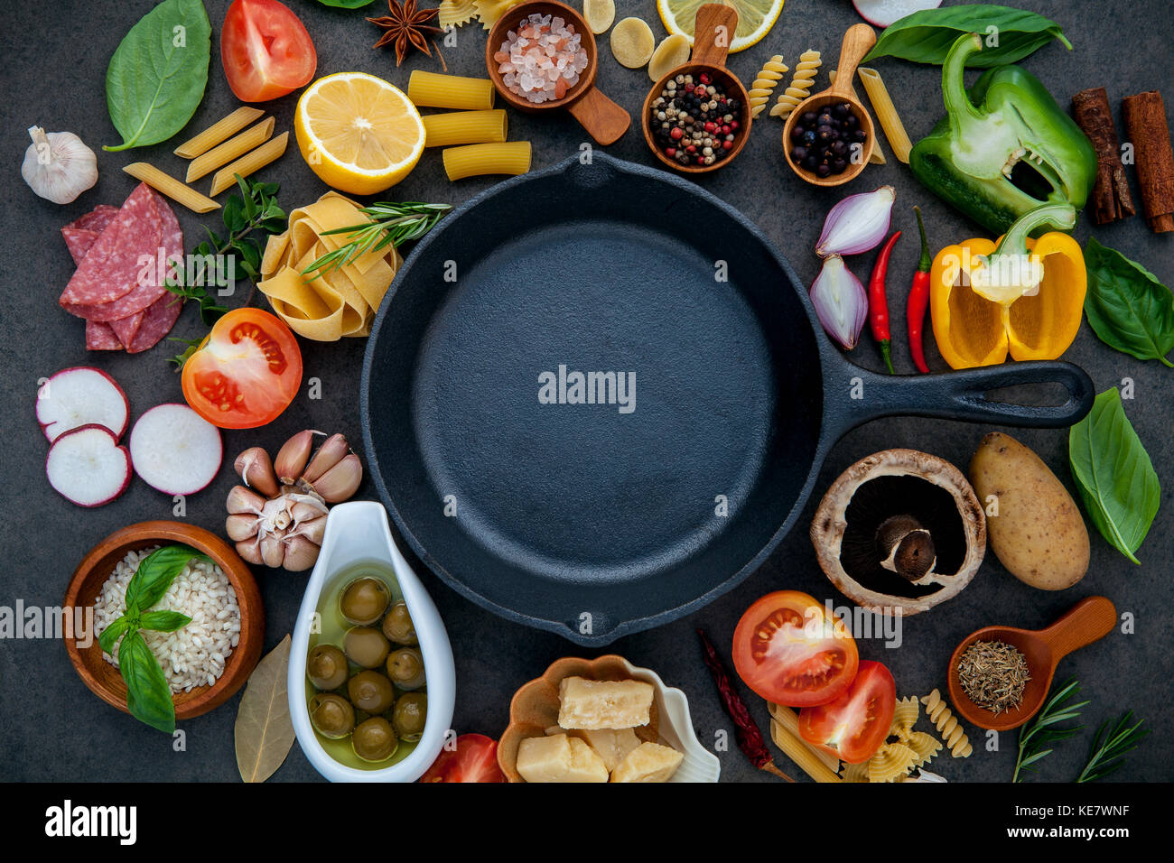 Italian food cooking ingredients on dark stone background with iron pan ...
