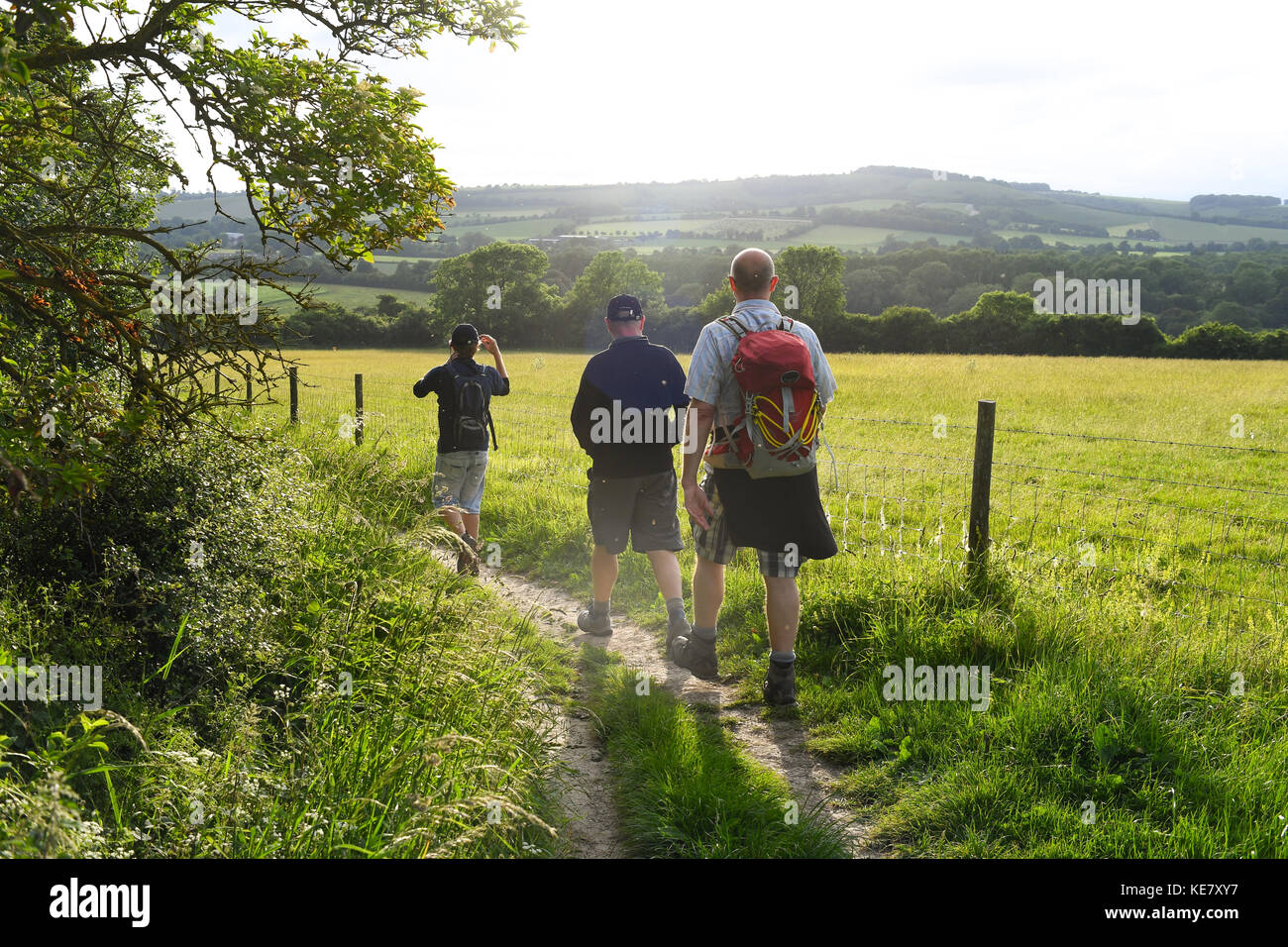 Three middle-aged men walking across the South Downs way between ...