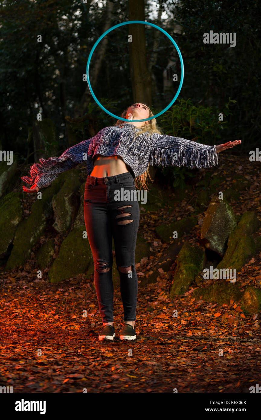 Girl rolls a hoop across her chest, hoop is suspended in mid air, with ...
