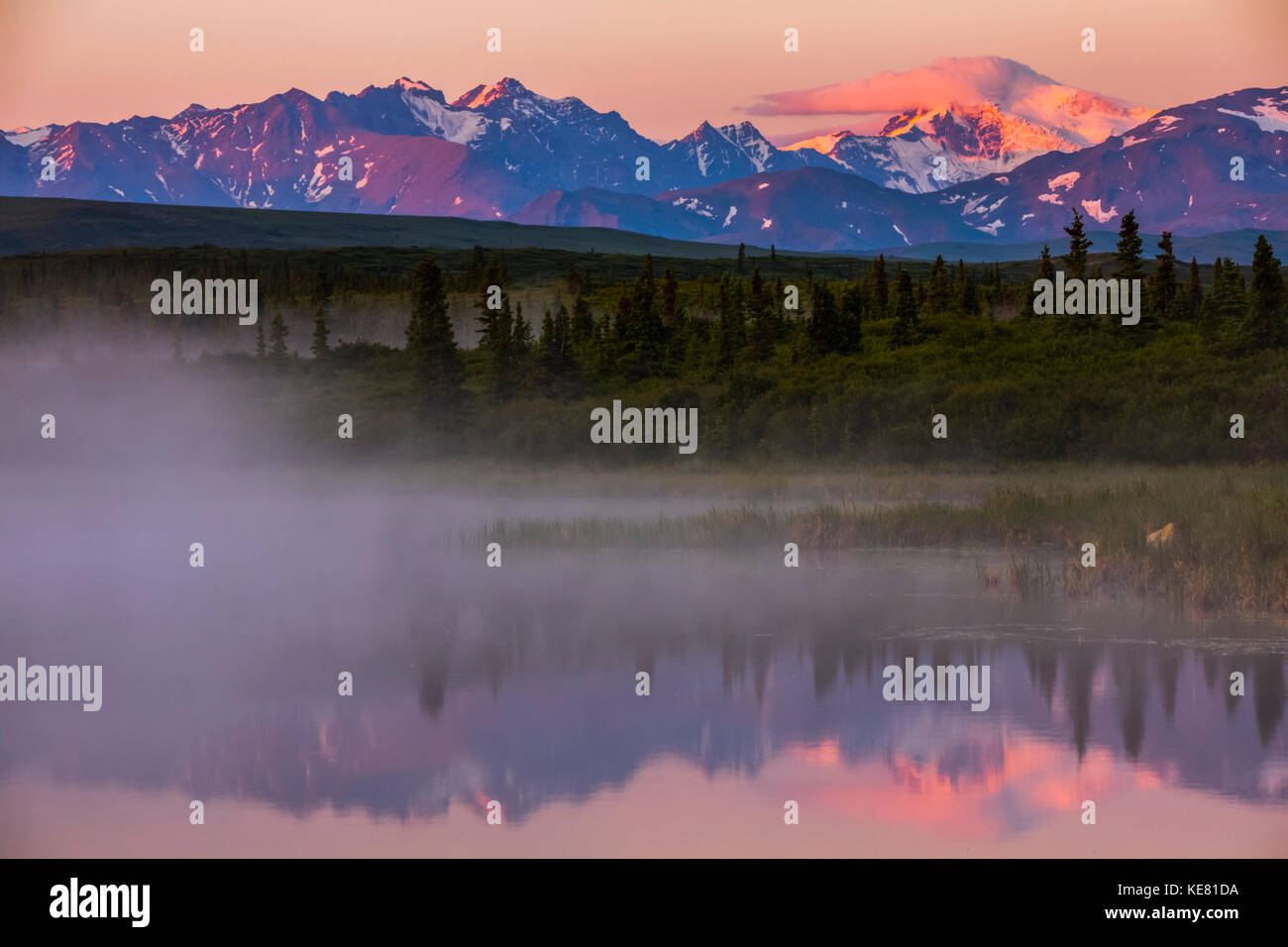 Fog rises off of Donnelly Lake at sunrise with the Alaska Range in the ...