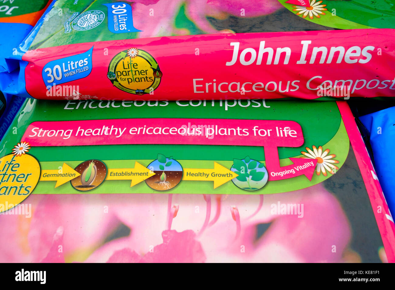 A stack of bags of Westland John Innes ericaceous compost in a garden ...