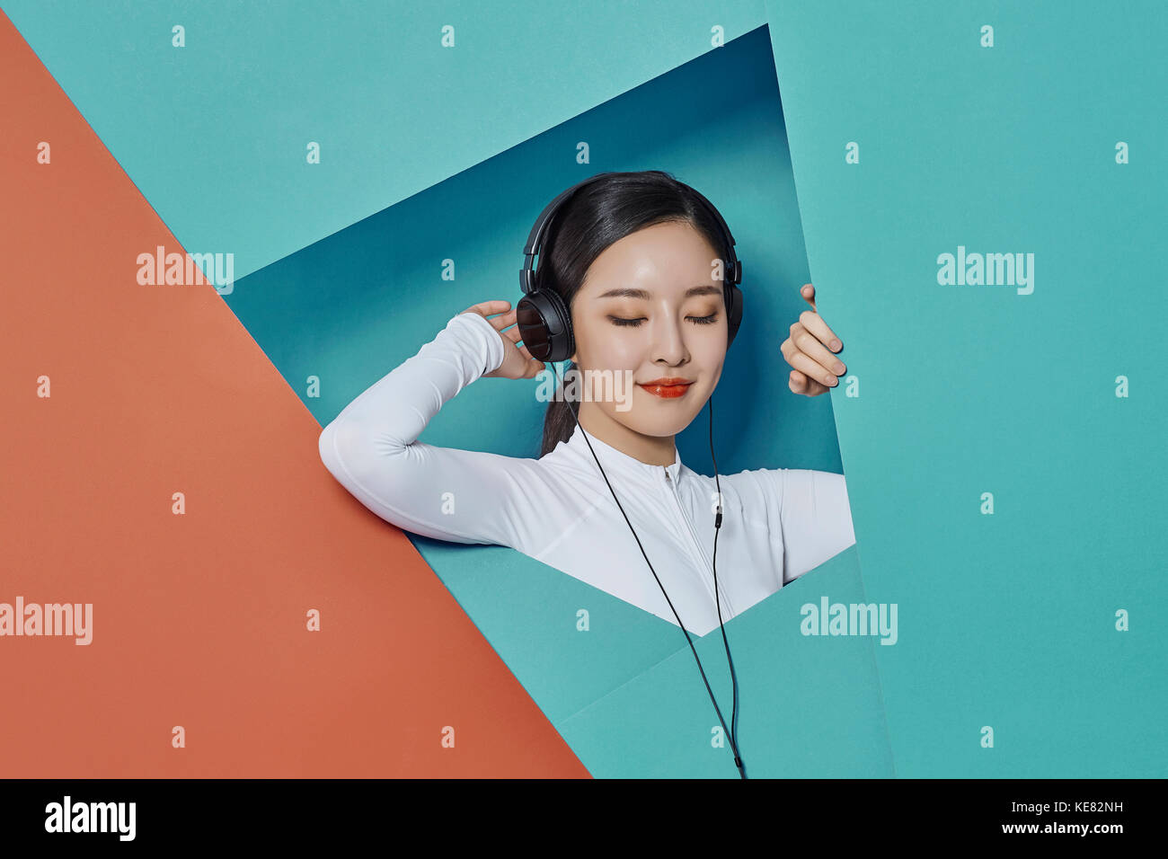 Portrait of young smiling woman listening to music closing her eyes ...