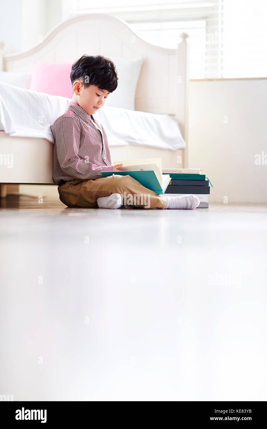 Side view of boy sitting reading book Stock Photo - Alamy