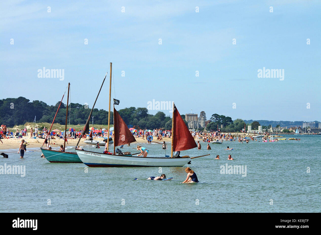 Families bathing and on Studland bay beach, Branksea castle on Brownsea ...