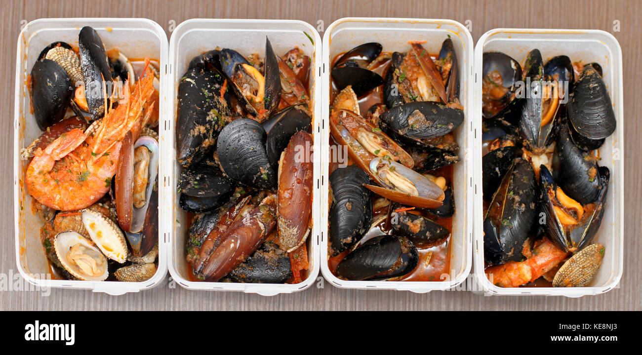 Sea shells and crustacean cooked and served in white plastic containers ...