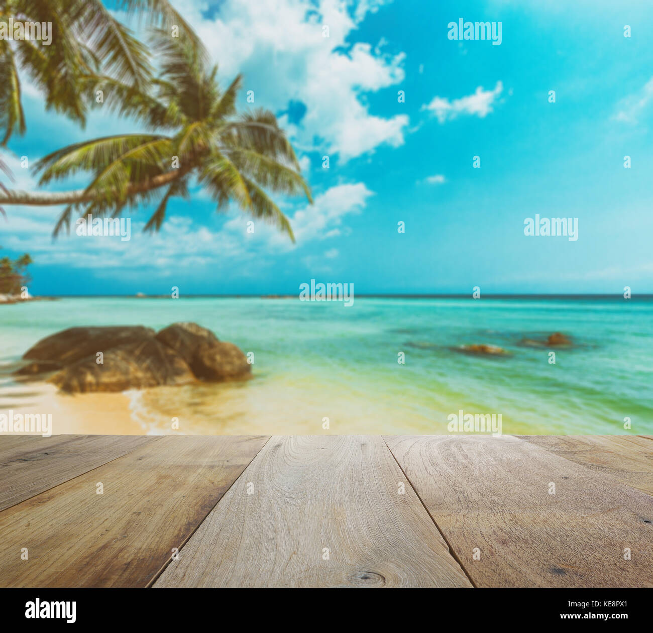 wooden table top with blur of beautiful tropical beach with coconut ...