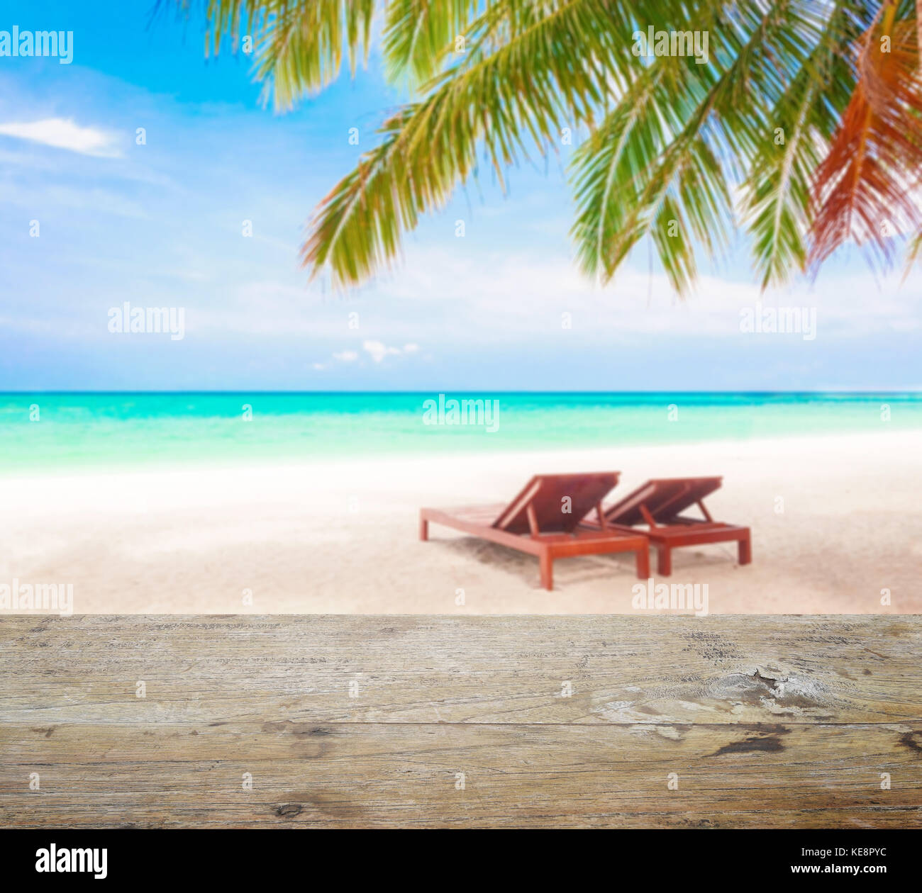 wood table top on blur beach background with beach chairs under coconut ...
