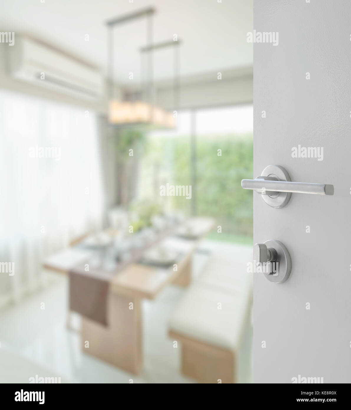 opened white door to dining table and comfortable chairs in modern home ...