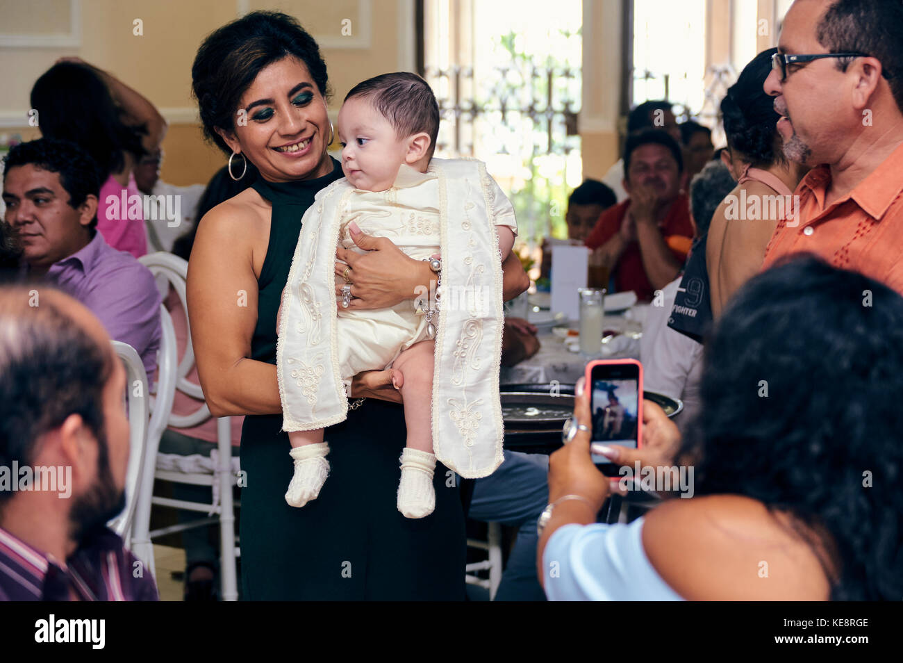 Guests having their picture taken with the just christened baby at his ...