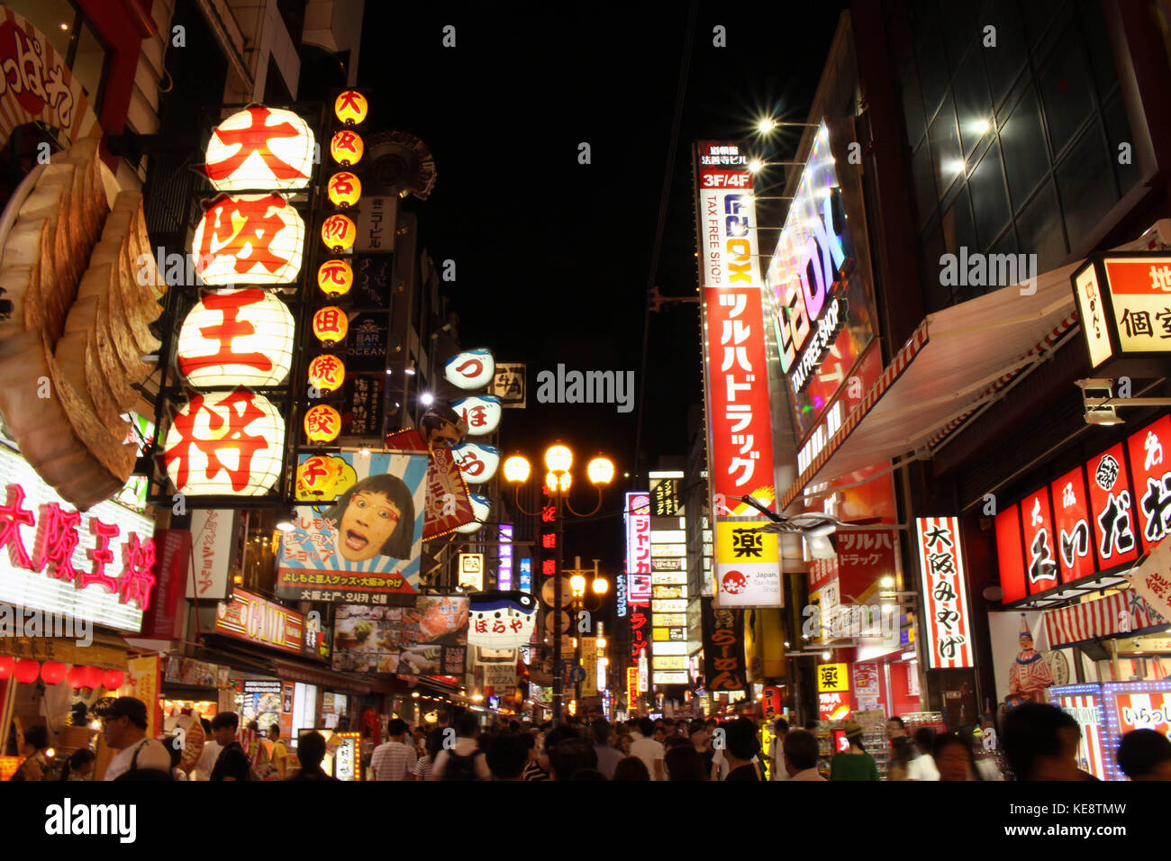 the crowded and bright Osaka at night. People, which are locals and ...