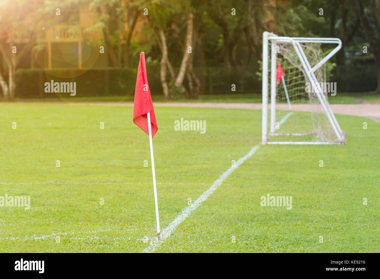 outdoor green soccer field showing red corner flag and goal with warm ...