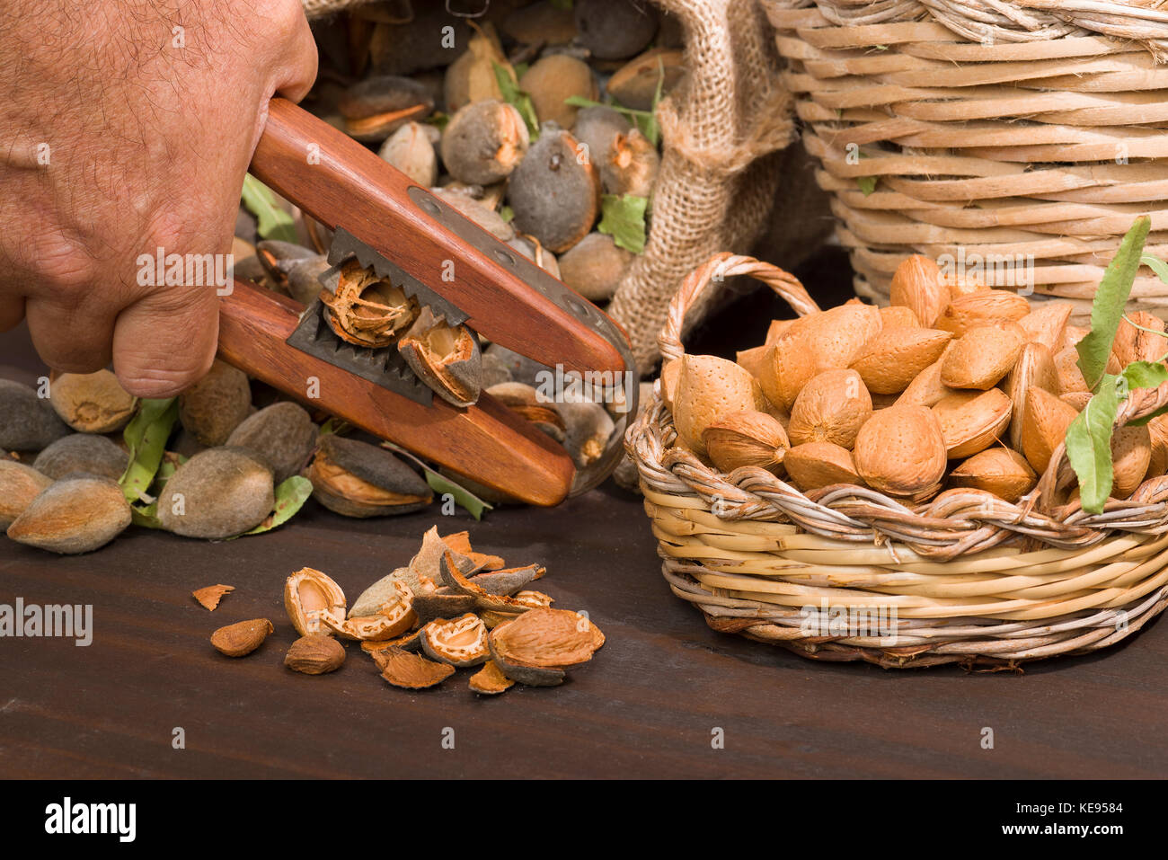 Almonds over a rustic wooden board. Rustic sack and basket. Nutcracker ...